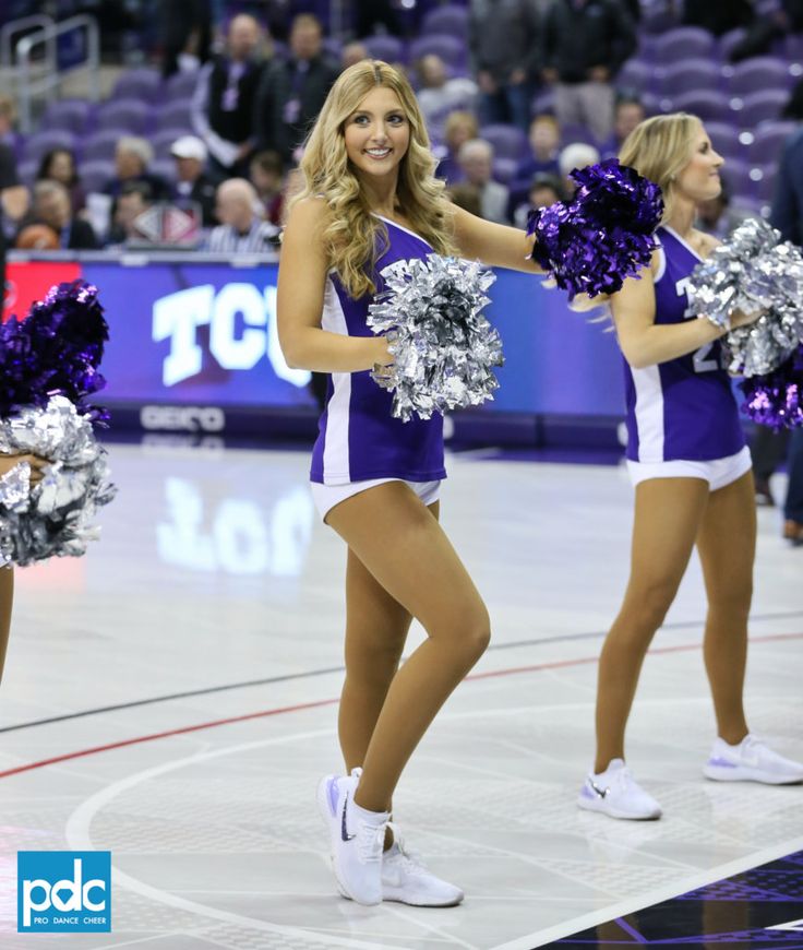 Two Cheerleaders In Purple And Silver Outfits On The Court With Their Pom Poms