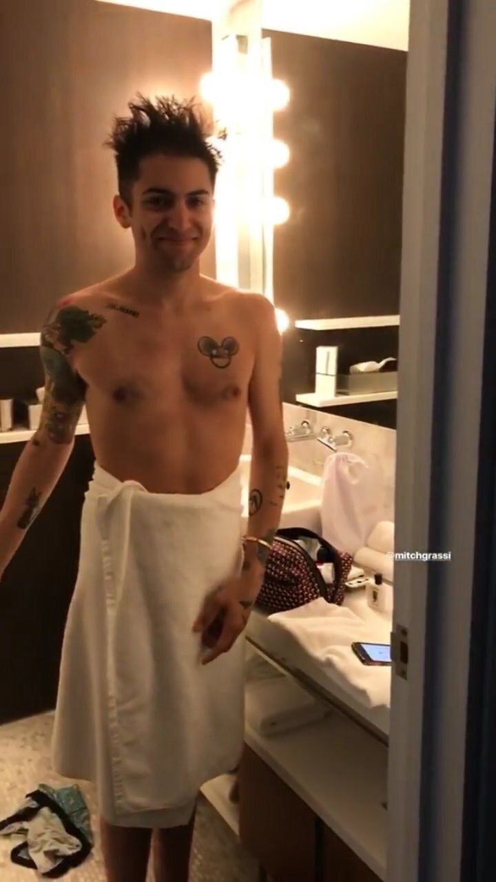 A Man In A Towel Standing In Front Of A Bathroom Mirror And Looking At The Camera