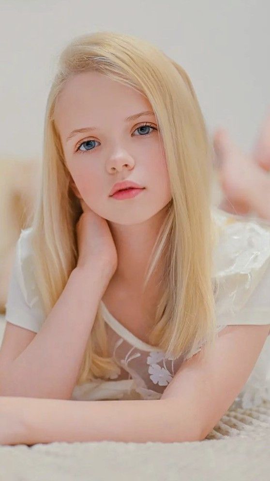 A Young Blonde Woman Laying On Top Of A Bed