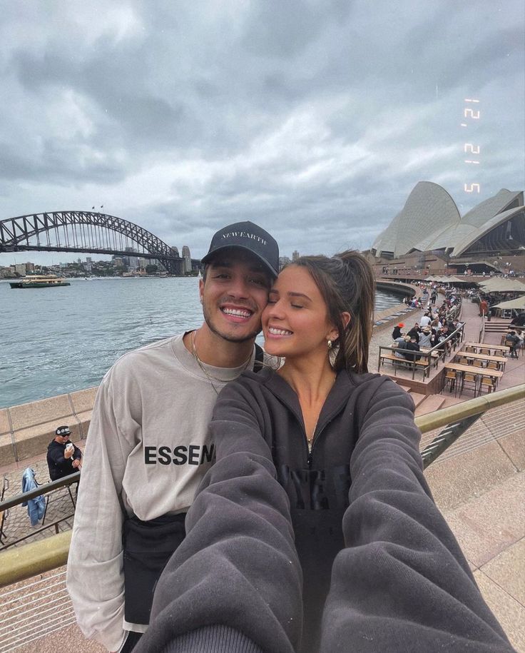 A Man And Woman Taking A Selfie In Front Of The Sydney Harbour