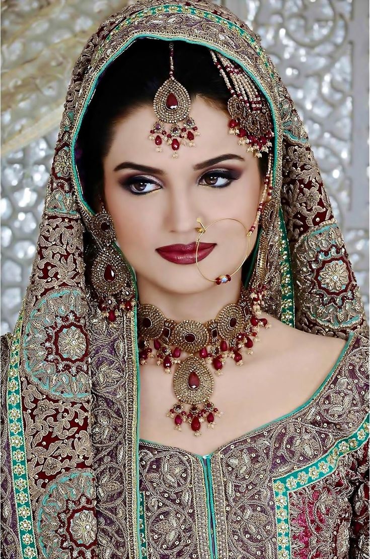 A Woman Wearing A Red And Green Bridal Outfit With Jewelry On Her Head Posing For