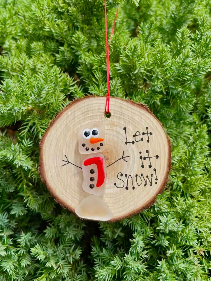 A Wooden Ornament With A Snowman On It And The Words Let It Snow