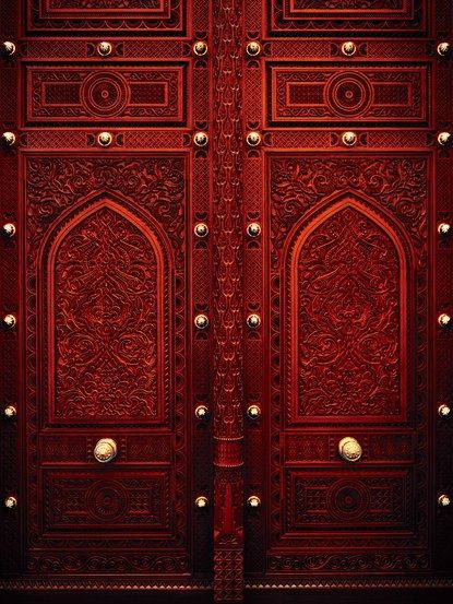 An Intricately Designed Red Door With Gold Hardware