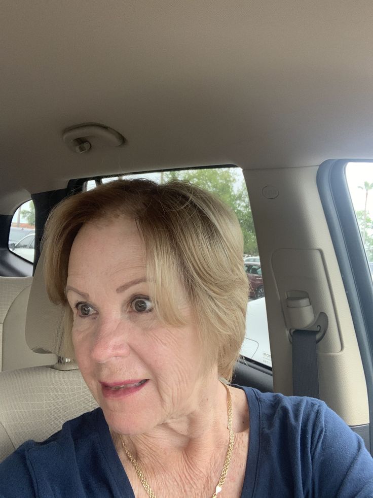 An Older Woman Sitting In The Back Seat Of A Car Looking At The Camera And Smiling
