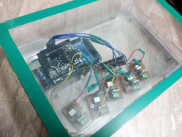 An Electronic Device Is In A Clear Box On The Table With Wires And Other Electronics