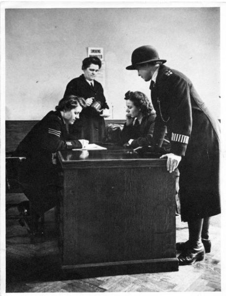 An Old Black And White Photo Of Some People In Front Of A Desk With Papers