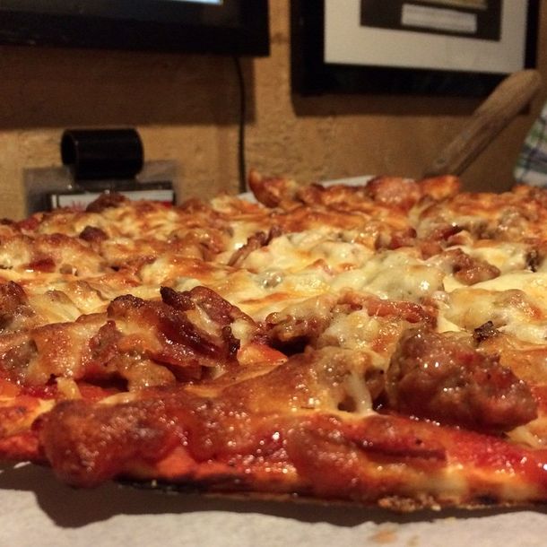 A Large Pizza With Meat And Cheese On It