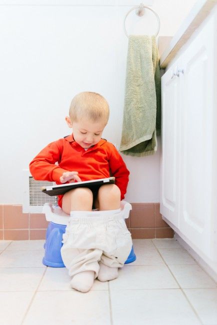 a young boy sitting on top of a blue potty seat next to a white cabinet a young boy sitting on top of a blue potty seat next to a white cabinet