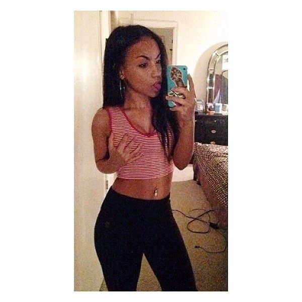 A Woman Taking A Selfie With Her Cell Phone In Front Of Her Face And Wearing Black Pants