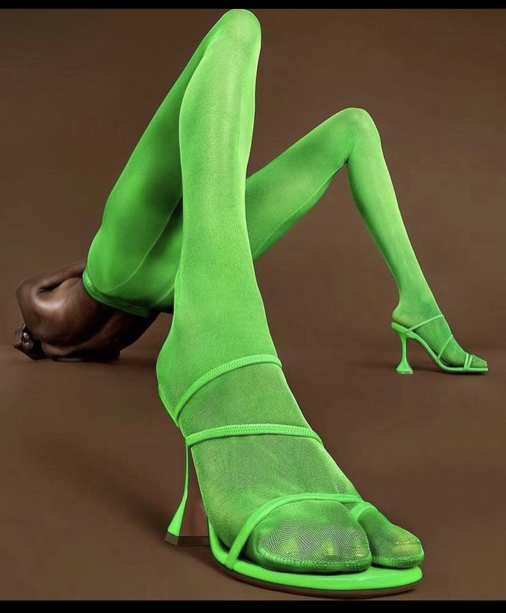 A Woman In Neon Green Stockings And High Heeled Shoes Laying On The Ground With Her Legs Crossed