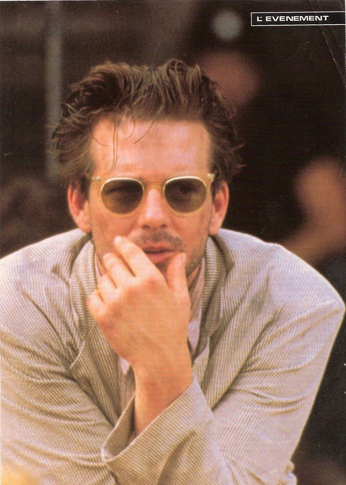 A Man Wearing Sunglasses Sitting Down With His Hand On His Chin