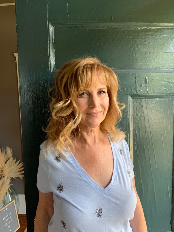 A Woman Standing In Front Of A Green Door With Her Hand On Her Hip And Looking At The Camera