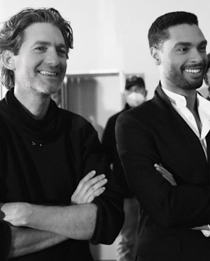 Two Men Standing Next To Each Other Smiling