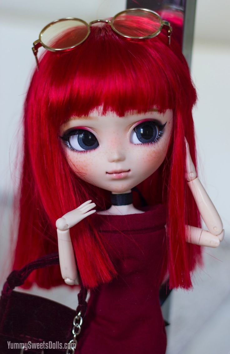 A Close Up Of A Doll With Red Hair And Glasses On Its Head