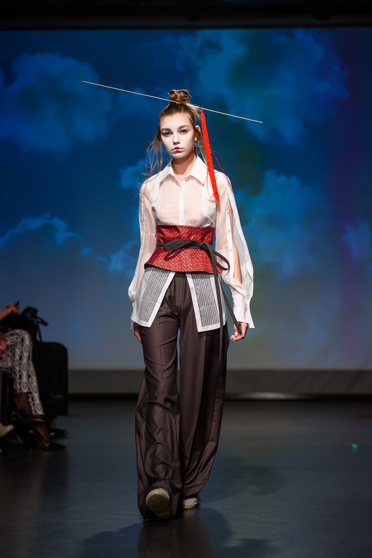 A Woman Is Walking Down The Runway In A White Shirt And Black Pants