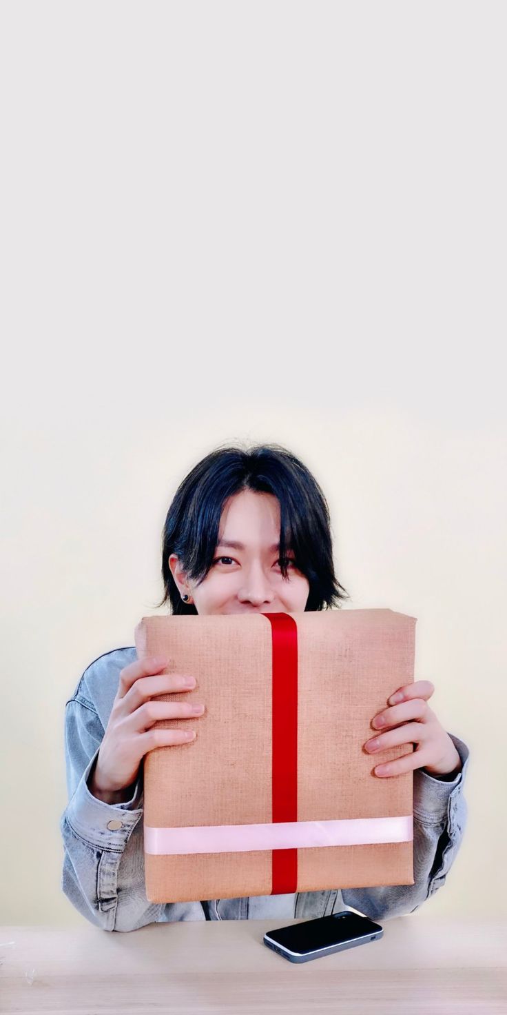A Woman Holding A Wrapped Present In Front Of Her Face