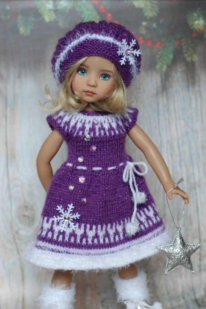 The Doll Is Wearing A Purple Dress And Hat With White Snowflakes On It