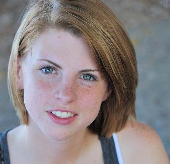 A Woman With Freckled Hair And Blue Eyes Is Posing For A Photo While Wearing A Tank Top