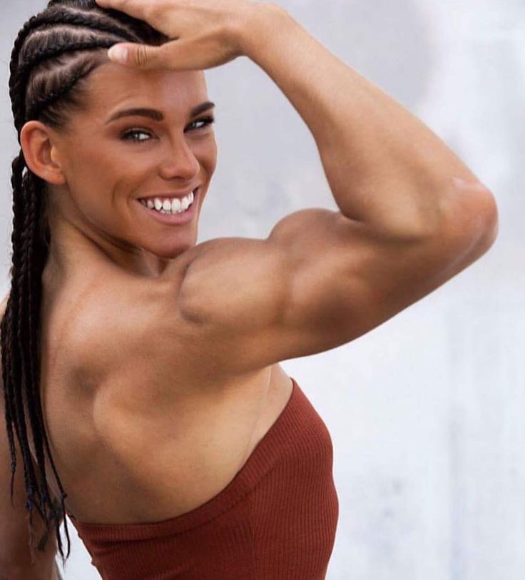 A Woman Posing For The Camera With Her Arms Behind Her Head
