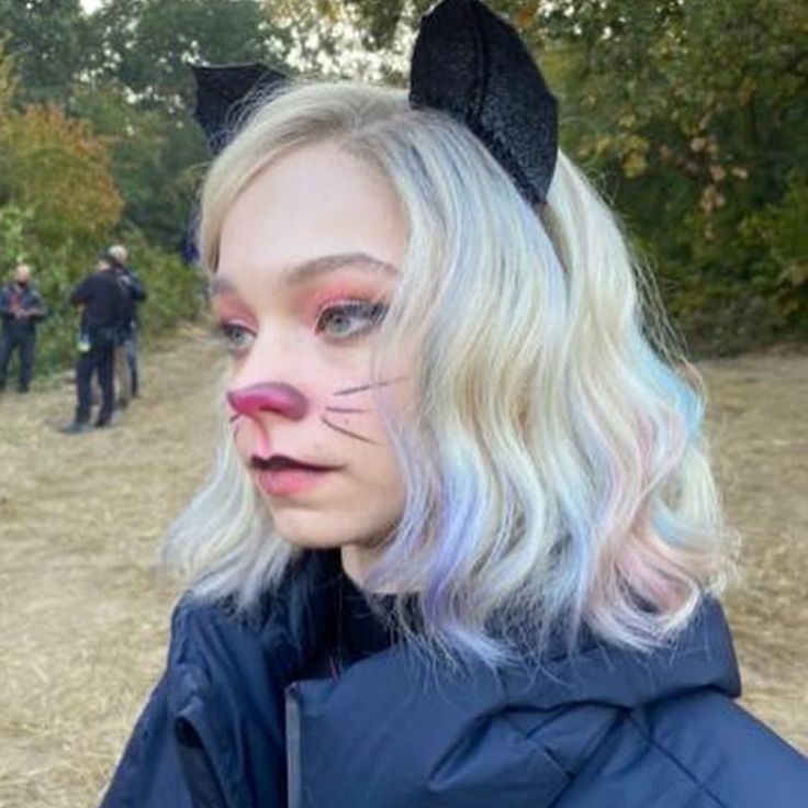 A Woman With Cat Ears On Her Head Wearing A Blue Jacket And Pink Makeup Looks At The Camera