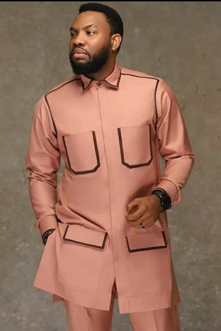 A Man In A Pink Suit And Black Tie Standing With His Hands In His Pockets