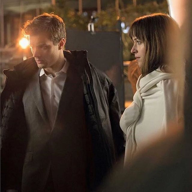 A Man And Woman Standing Next To Each Other In Front Of A Building At Night