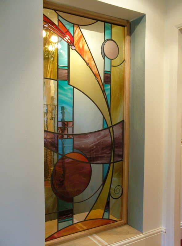 A Stained Glass Window In The Corner Of A Room With White Walls And Wood Flooring