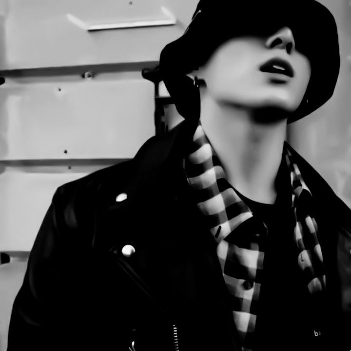 Black And White Photograph Of A Woman Wearing A Hat Scarf And Jacket In Front Of A Wall
