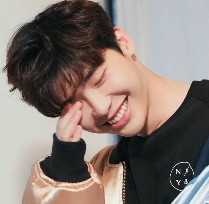 A Young Man Is Smiling And Holding His Hand To His Face