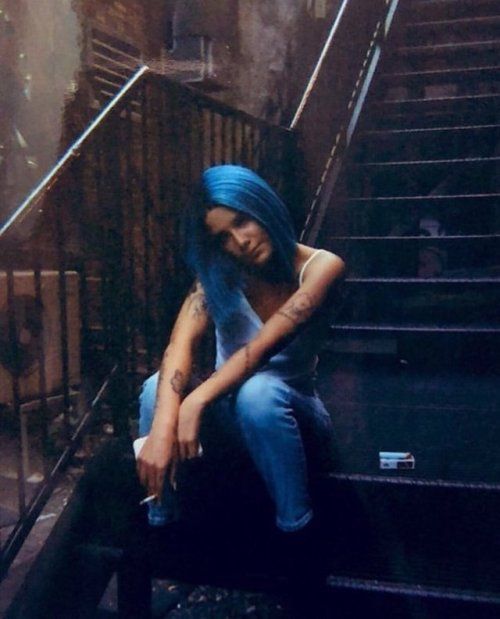 A Woman With Blue Hair Sitting On Some Stairs