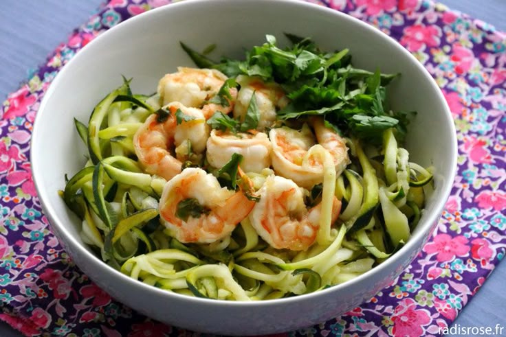 A White Bowl Filled With Pasta And Shrimp On Top Of A Colorful Table