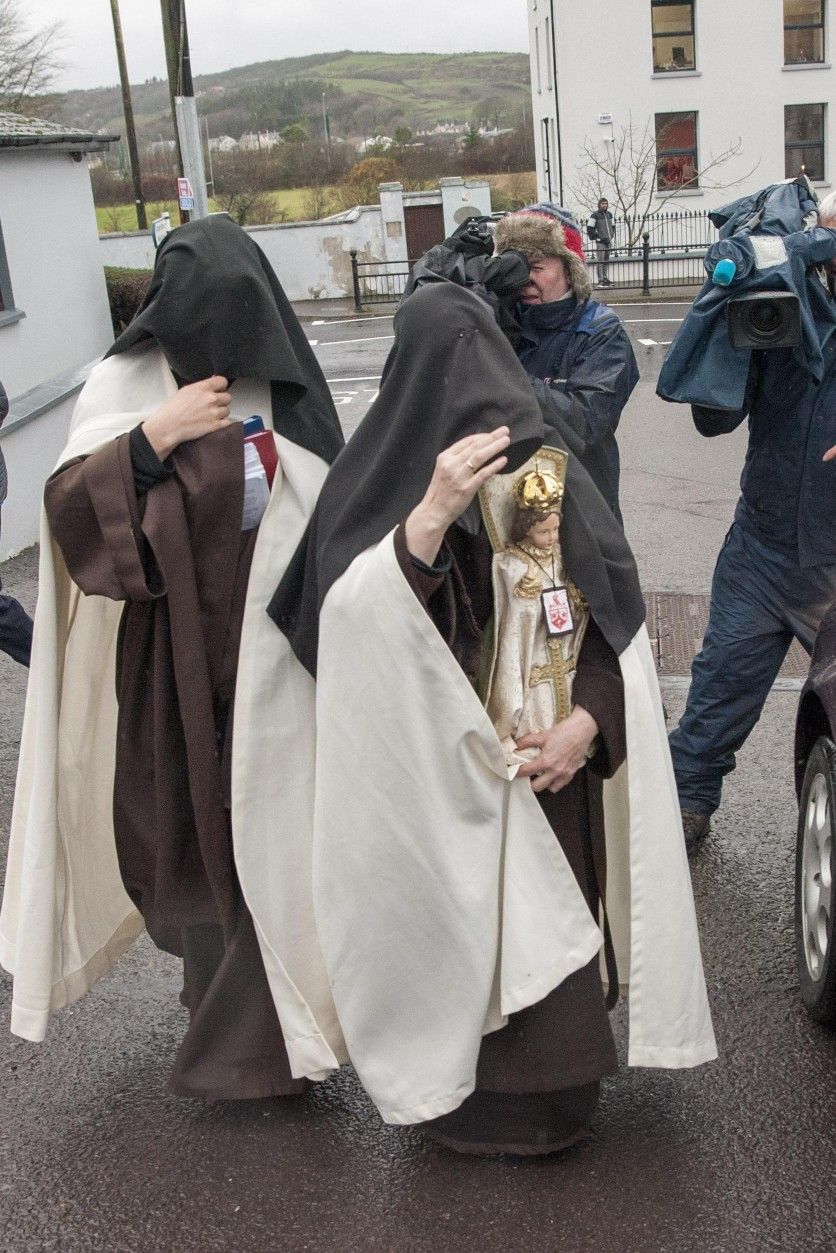 Three People Dressed In Costumes Walking With Cameras And Statue