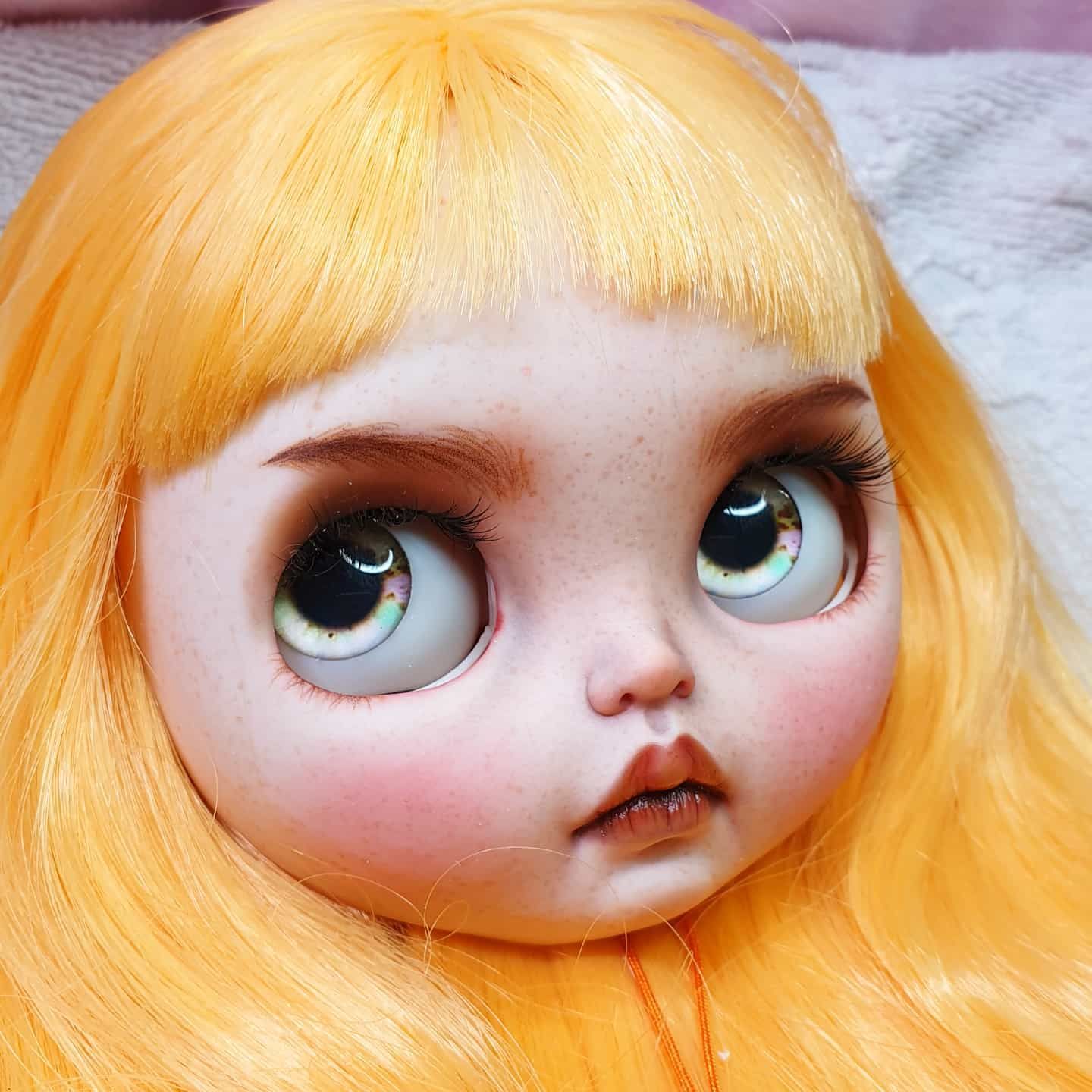 A Close Up Of A Doll With Long Blonde Hair And Big Blue Eyes Looking