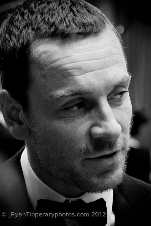 A Black And White Photo Of A Man In A Tuxedo Looking At The Camera